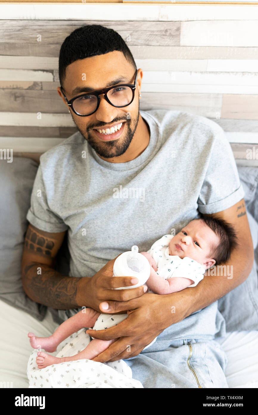 Portrait of happy father holding his newborn baby in bed Stock Photo ...
