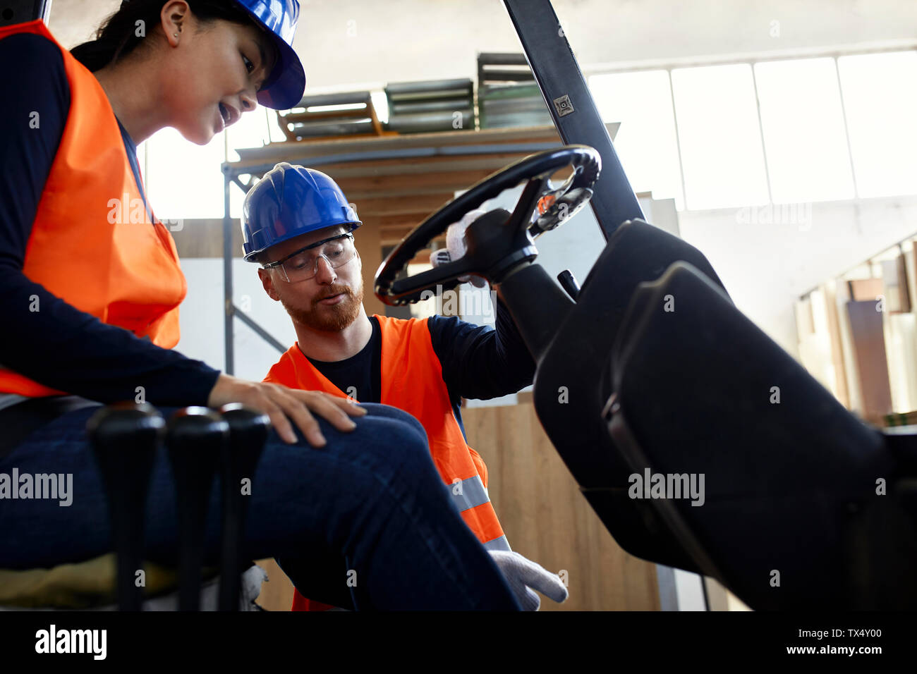 Man instructing female worker on forklift in factory Stock Photo - Alamy