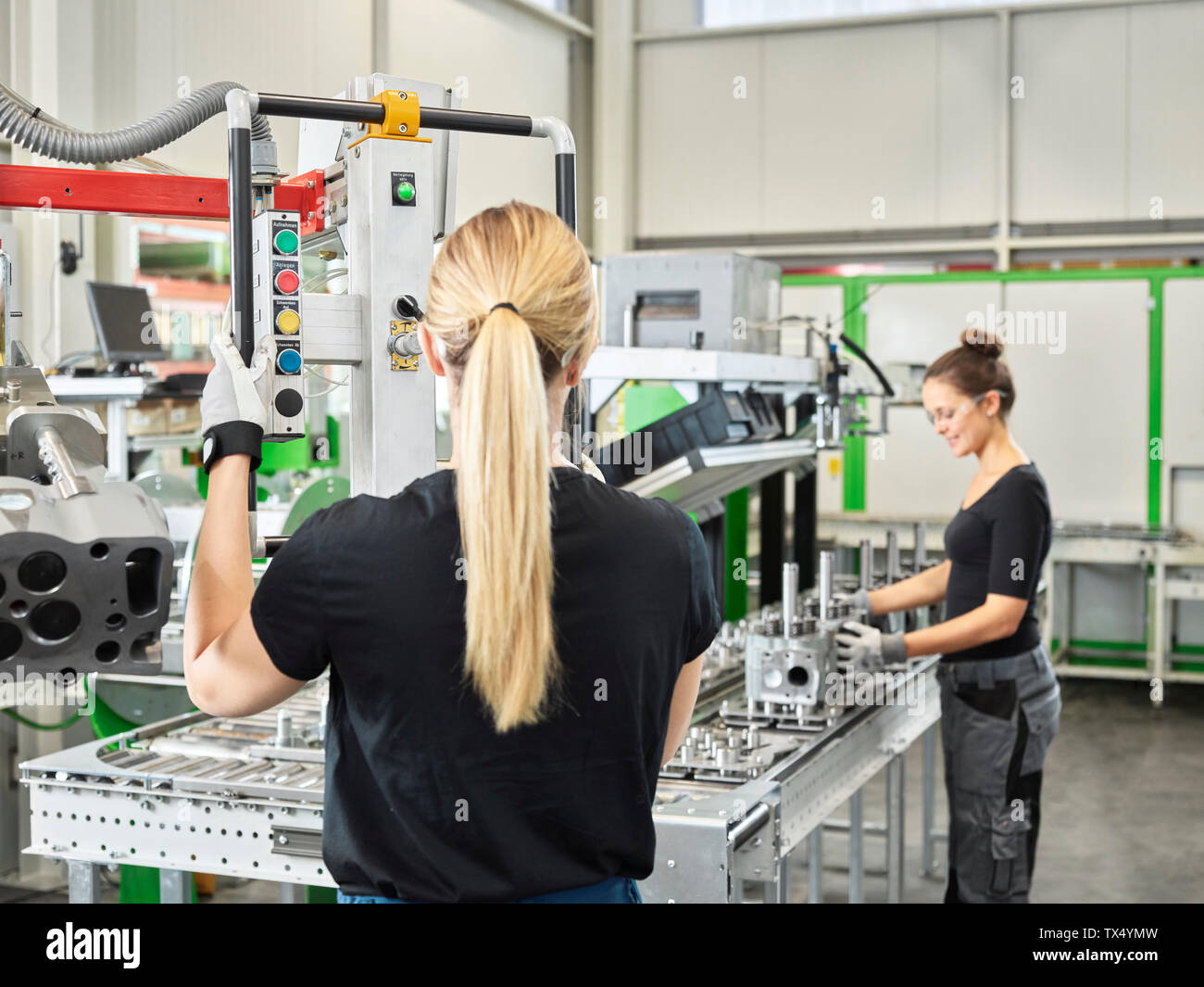 Two women working on a machine Stock Photo - Alamy