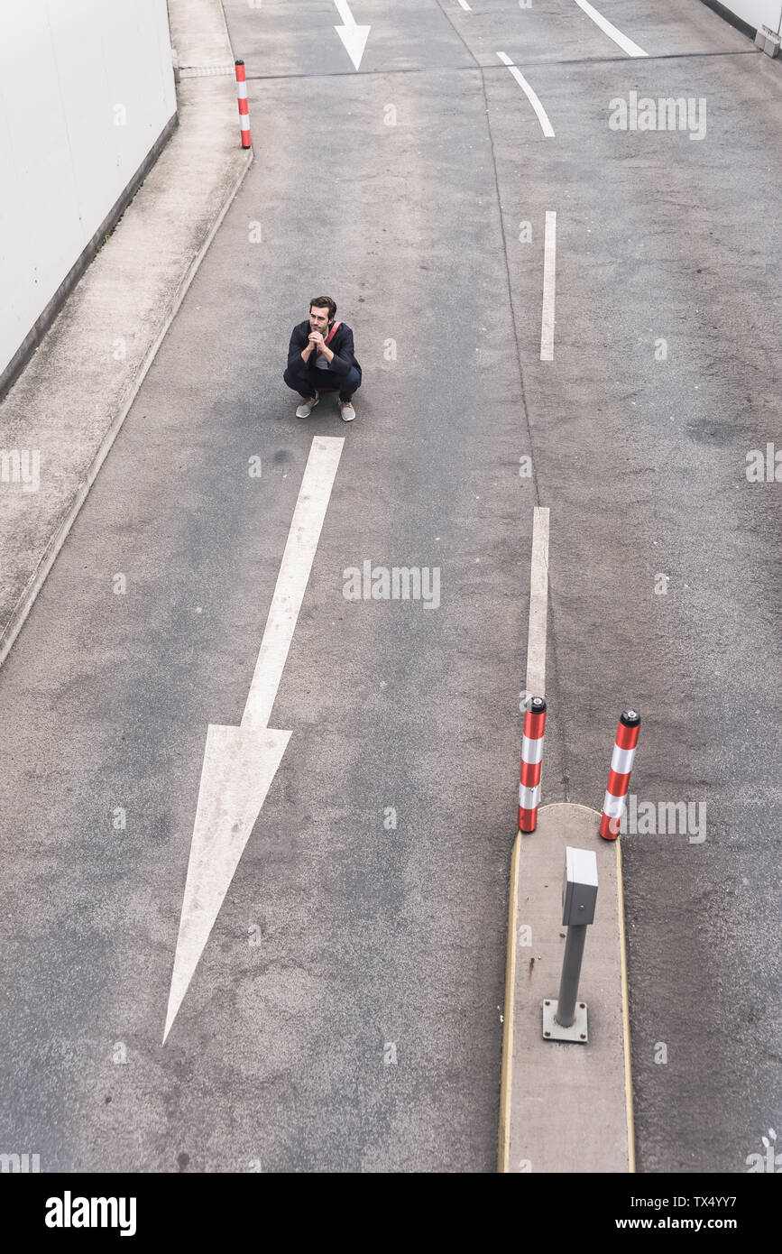 Businessman crouching on road with arrow sign Stock Photo - Alamy