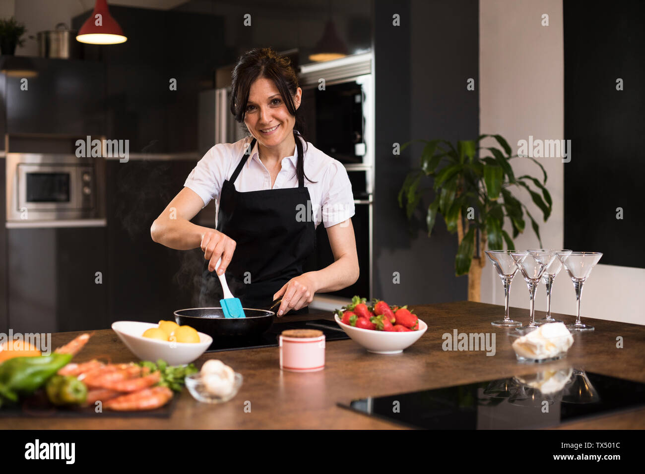 Portrait of smiling woman cooking in kitchen using a pan Stock Photo ...