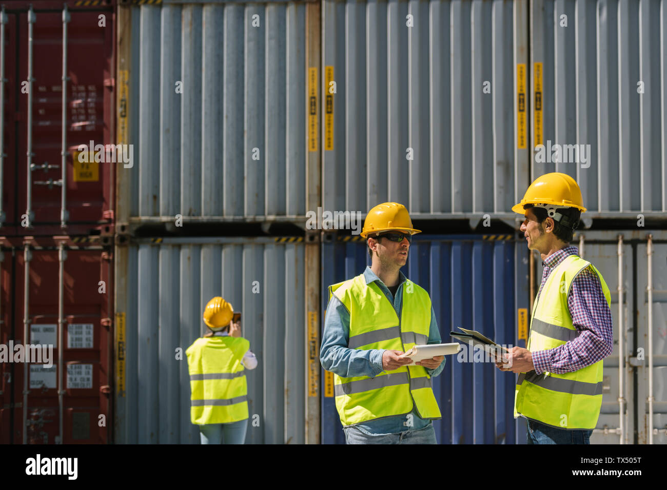 Workers talking near stack of cargo containers on industrial site Stock ...