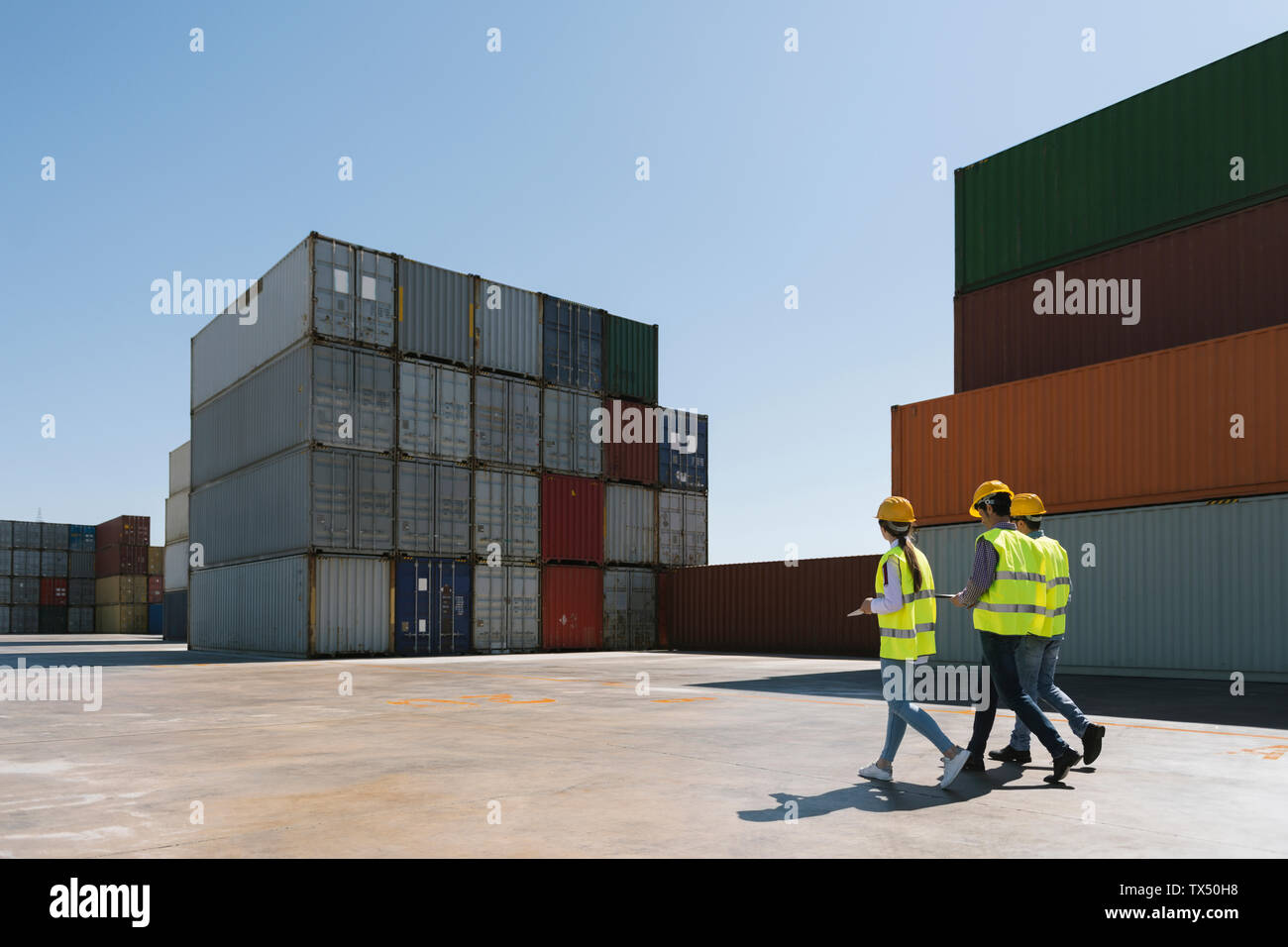 Workers walking together near stack of cargo containers on industrial ...