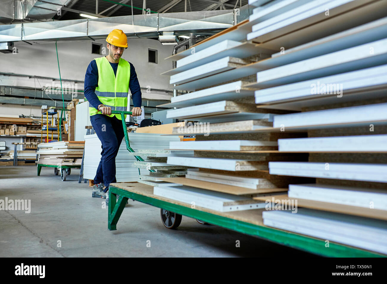 Worker pulling pallet jack with wooden boards in factory Stock Photo ...