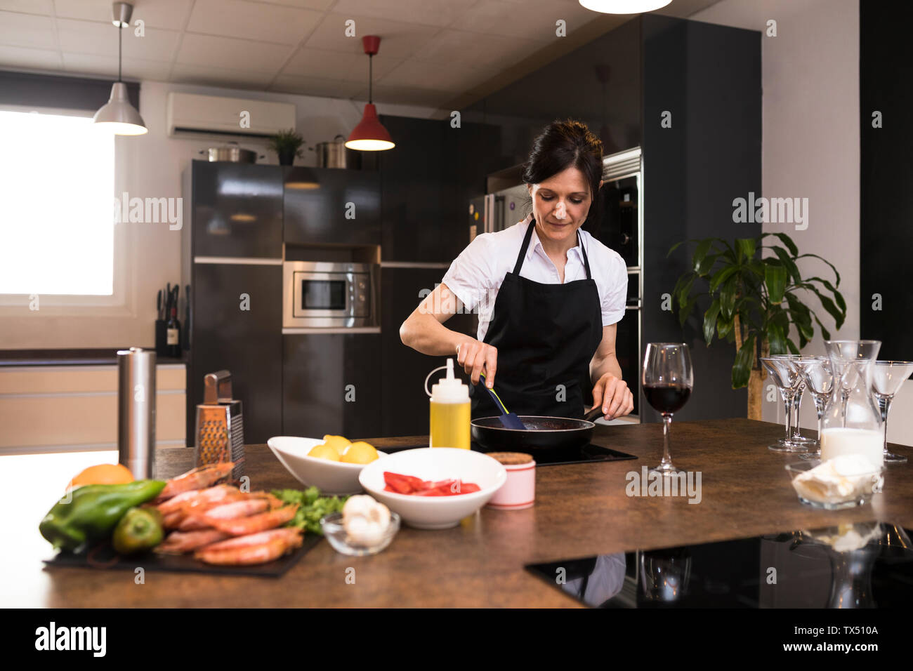 Woman cooking in kitchen using a pan Stock Photo - Alamy