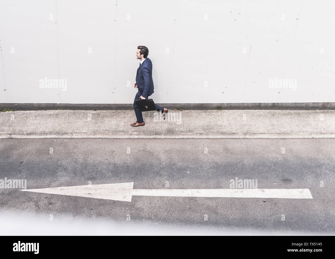 Businessman walking at road with arrow sign Stock Photo - Alamy