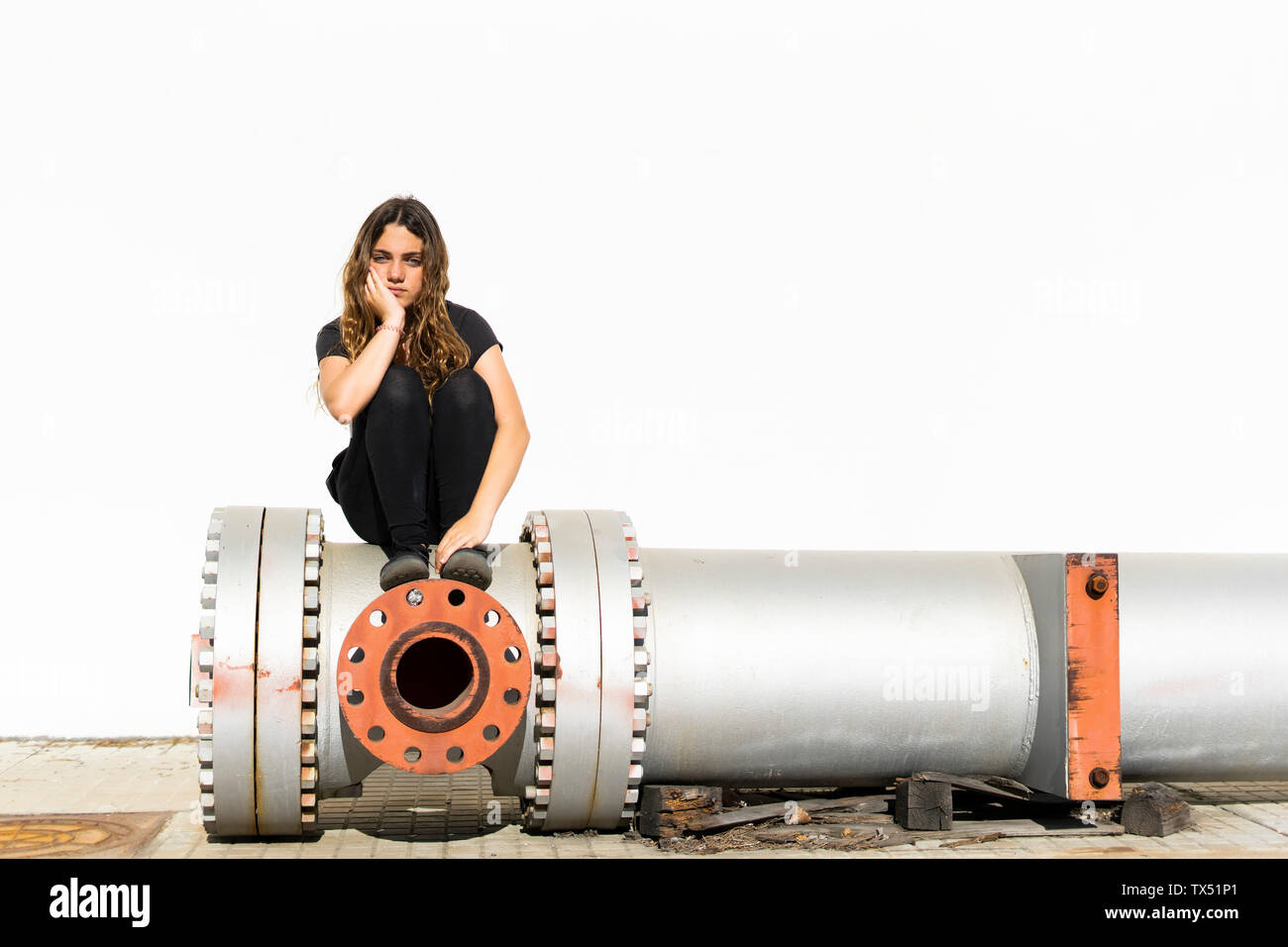 Portrait of serious teenage girl sitting on large pipe Stock Photo - Alamy