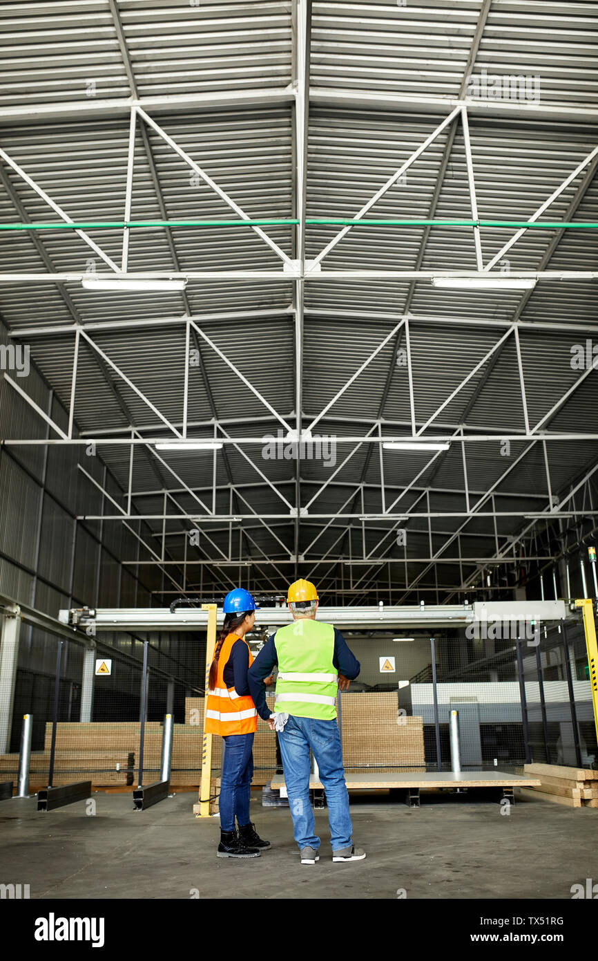 Rear view of male and female worker standing in factory workshop Stock ...