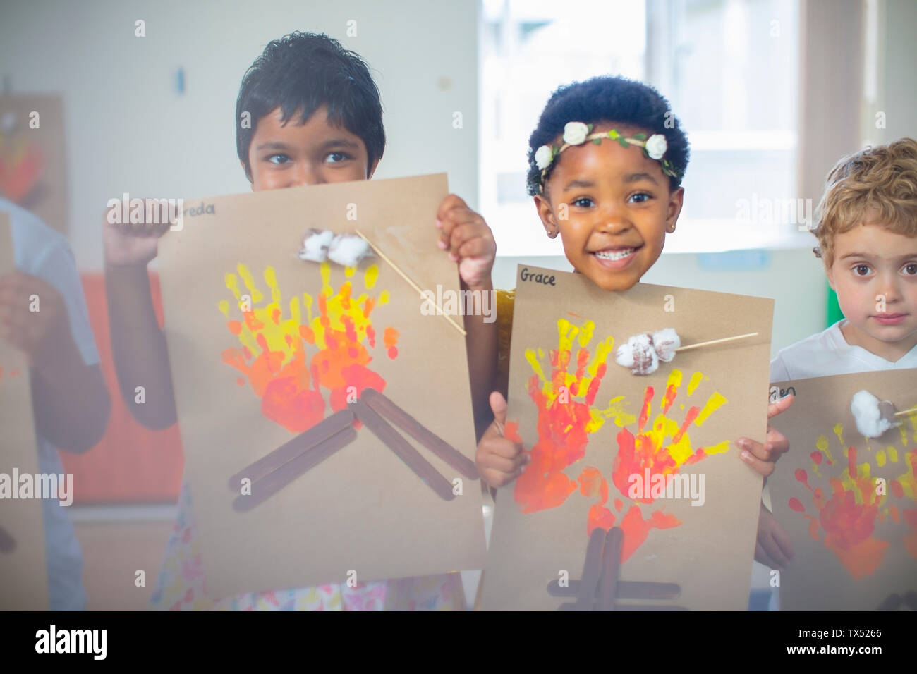 Portrait of smiling children presenting images of fire in kindergarten ...