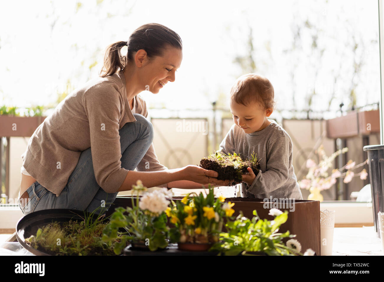 Mother and daughter planting flowers together on balcony Stock Photo ...