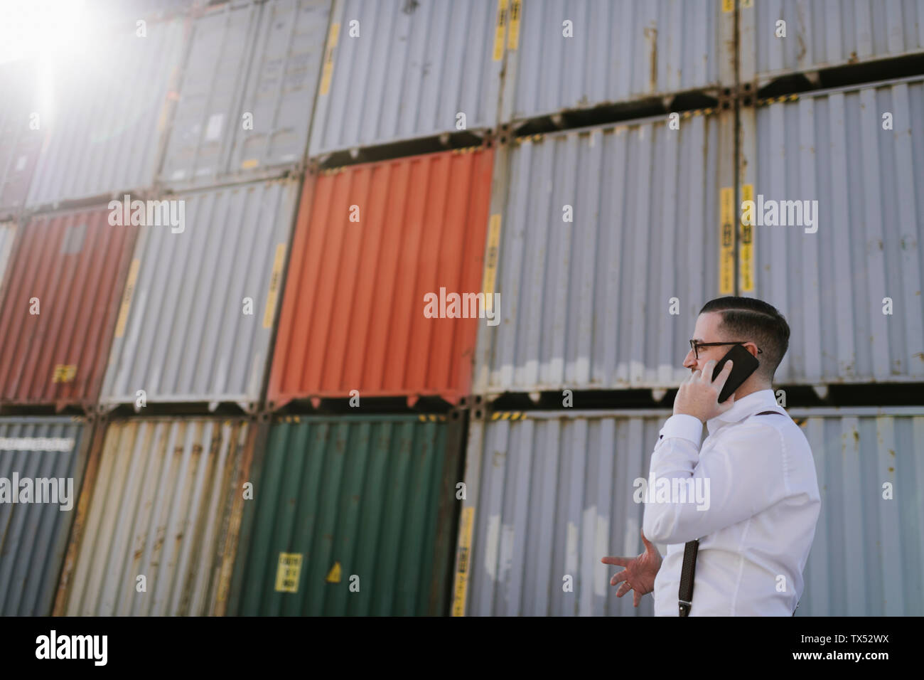 Manager talking on cell phone in front of cargo containers on ...