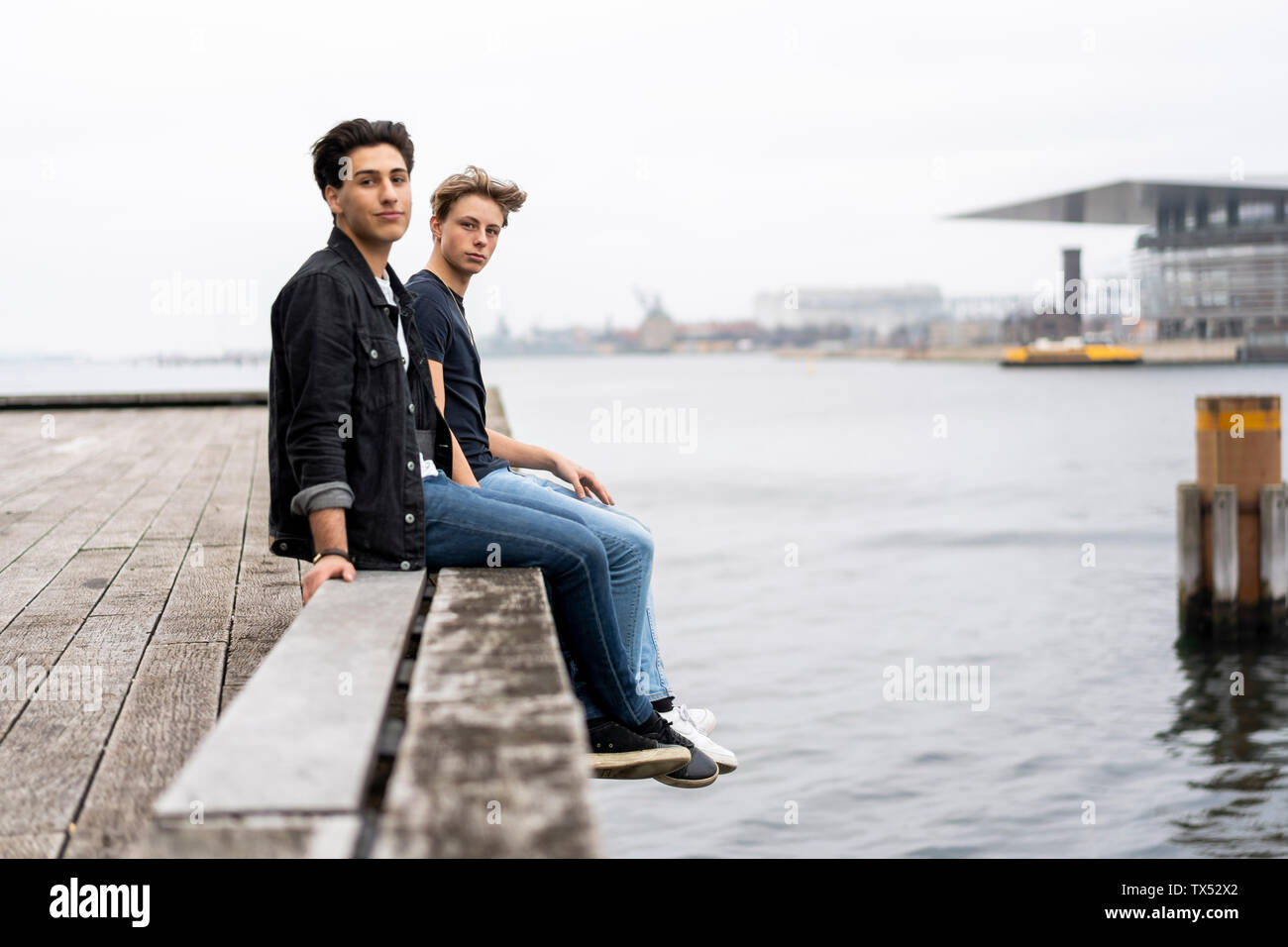 Denmark, Copenhagen, two young men sitting at the waterfront Stock ...