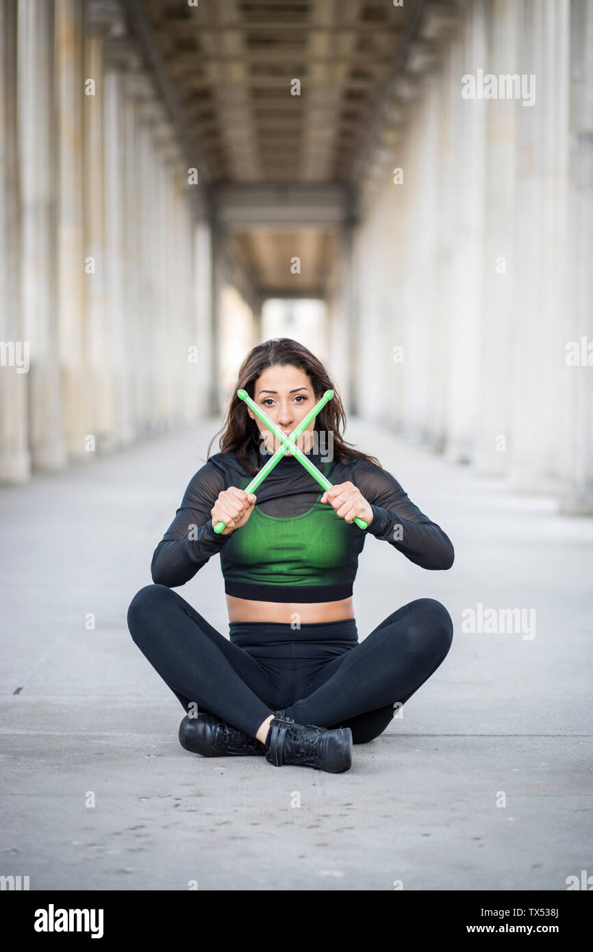 Young woman sitting on the ground holding pound exercise sticks Stock ...
