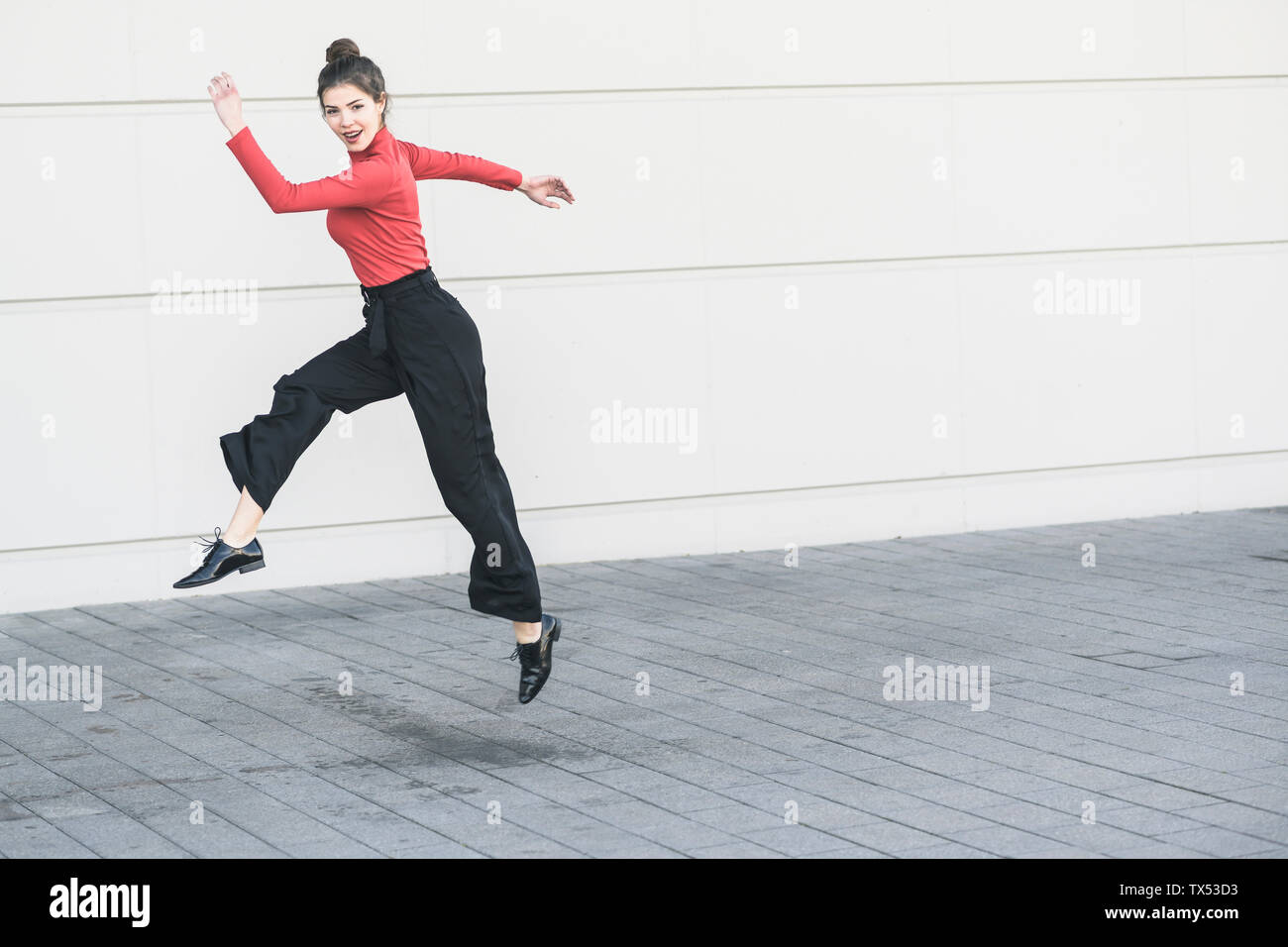 Elegant young women jumping in front of a wall Stock Photo - Alamy