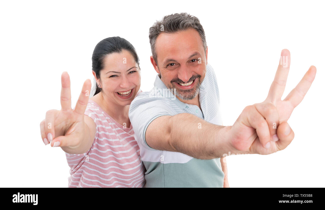 Smiling man and woman couple making peace or victory sign with fingers ...