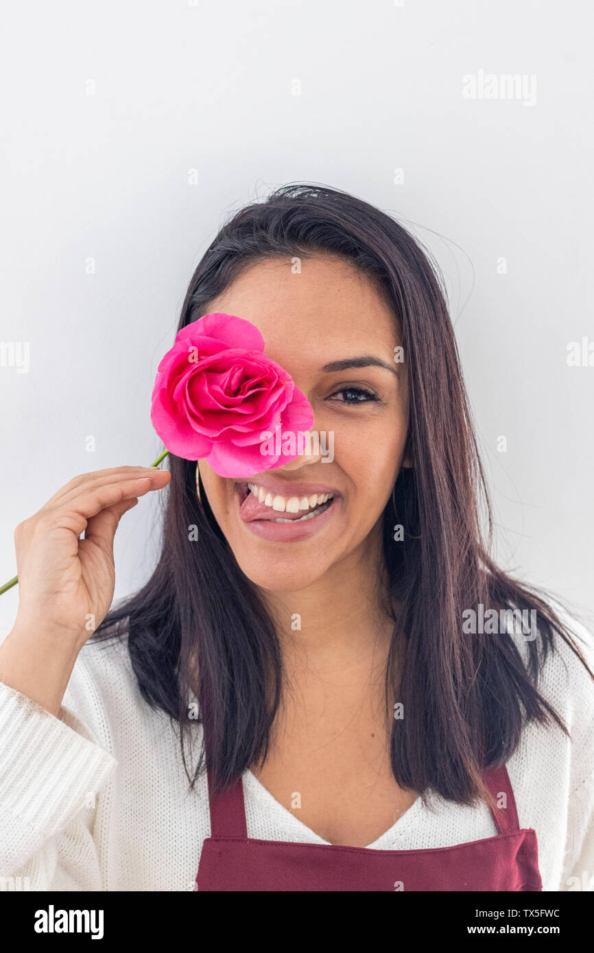 Cute smiling brunette playing with a red rose Stock Photo - Alamy