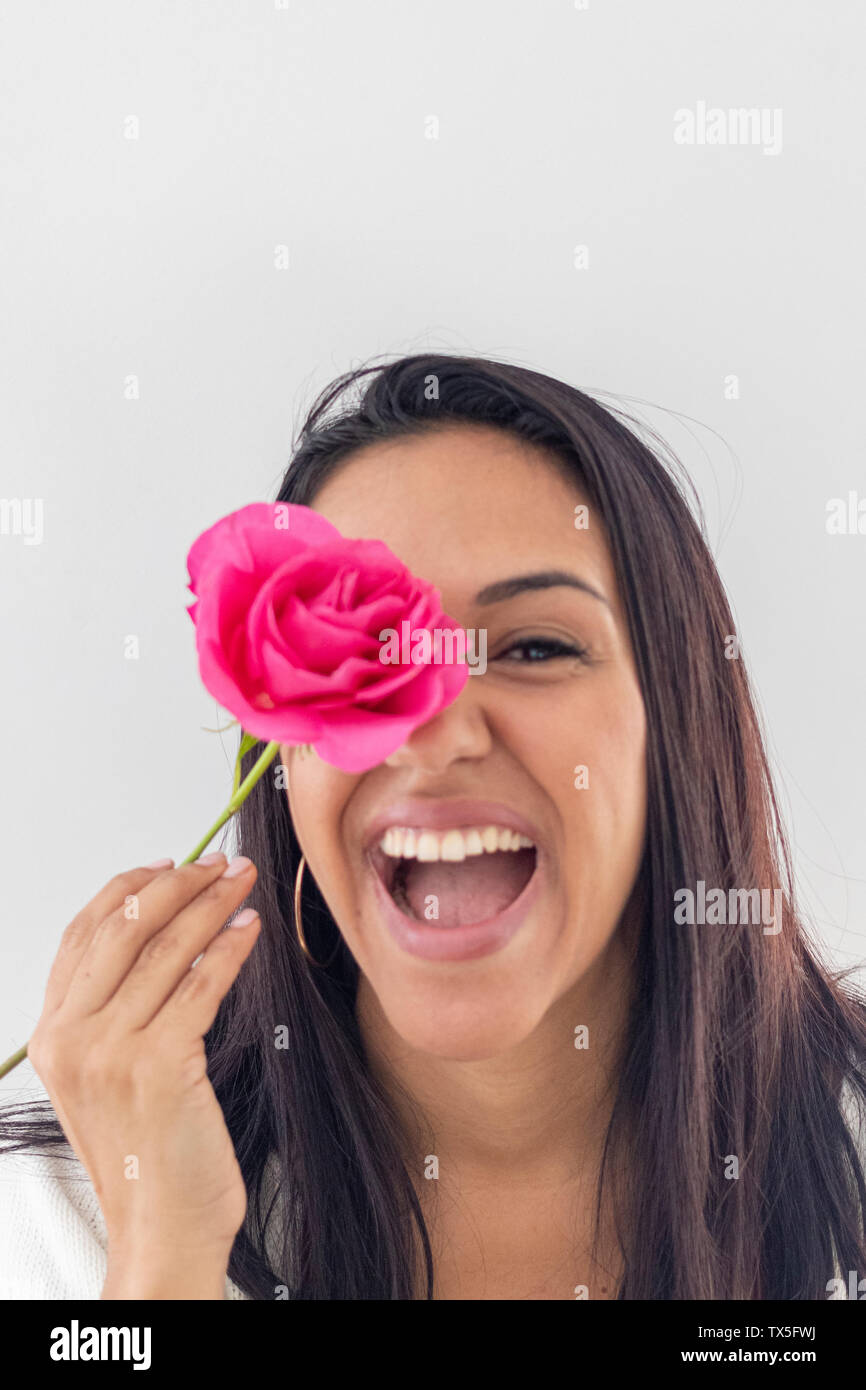 Cute smiling brunette playing with a red rose Stock Photo - Alamy