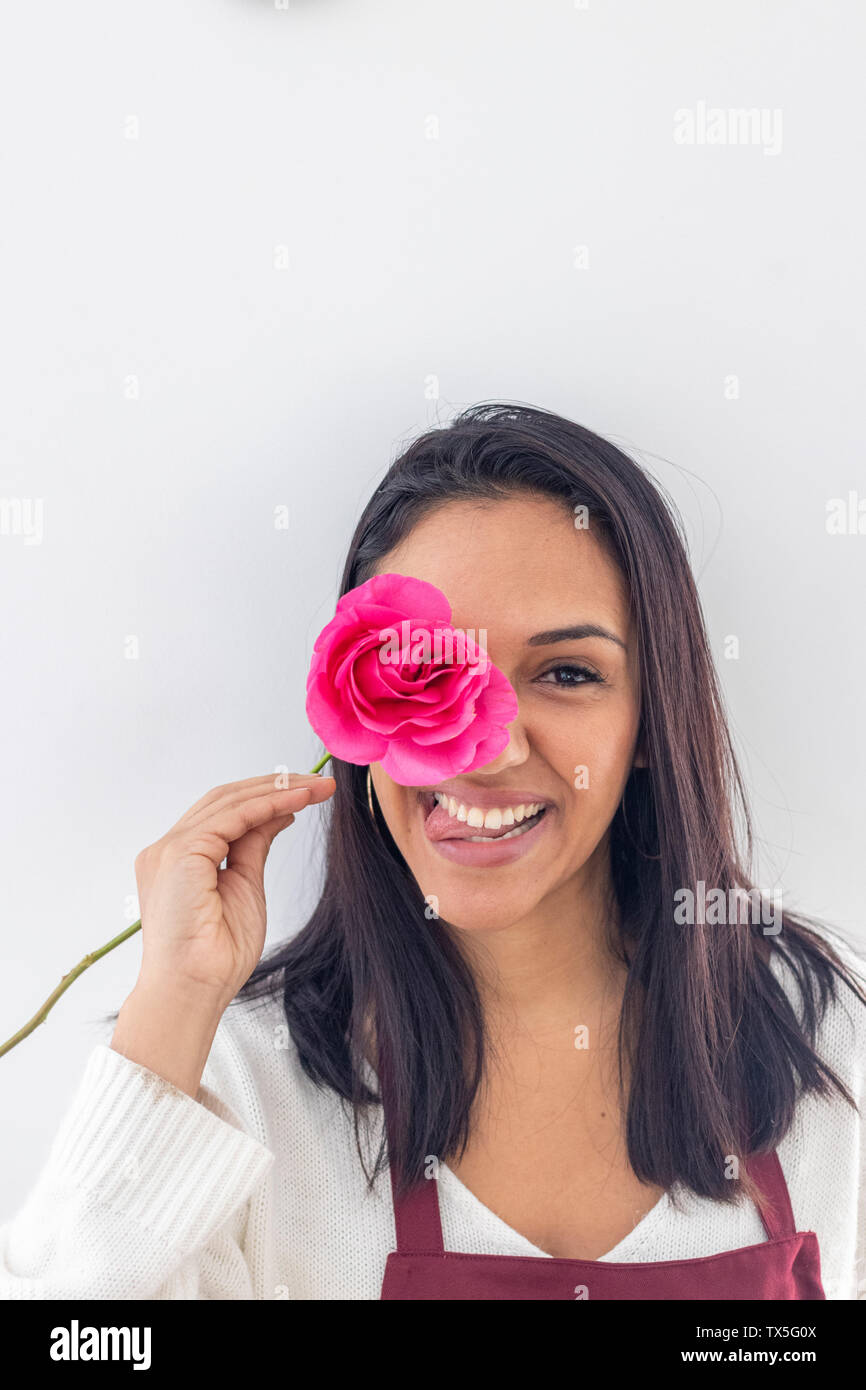 Cute smiling brunette playing with a red rose Stock Photo - Alamy