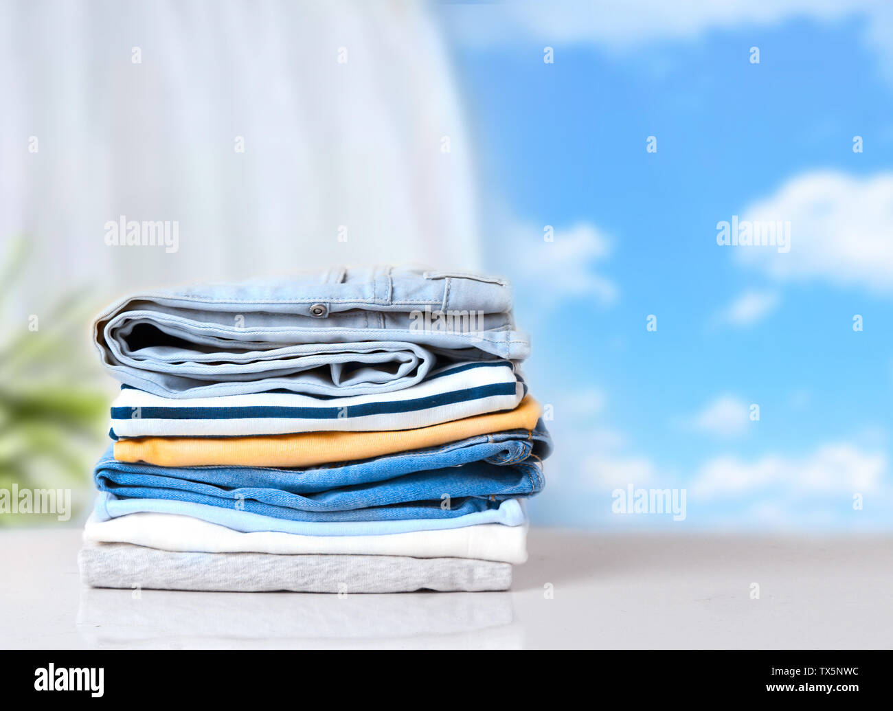 Stack cotton clothes on white table empty space background Stock Photo ...