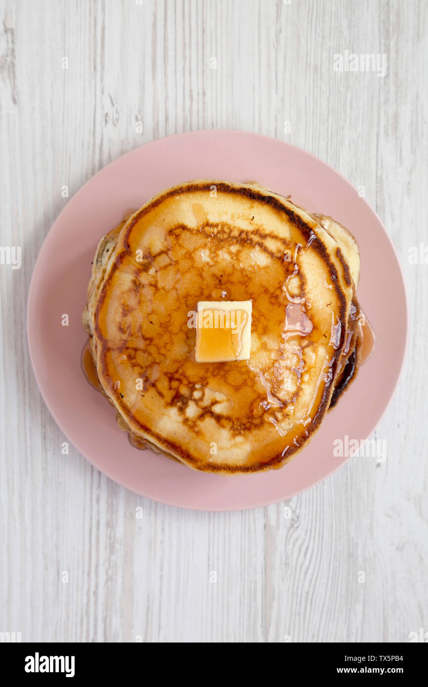 Homemade pancakes with butter and maple syrup on a pink plate over ...