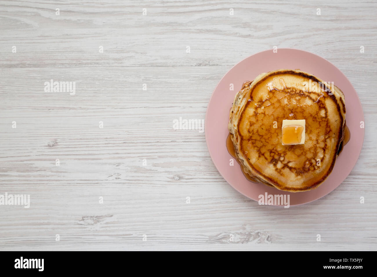 Homemade pancakes with butter and maple syrup on a pink plate, view ...