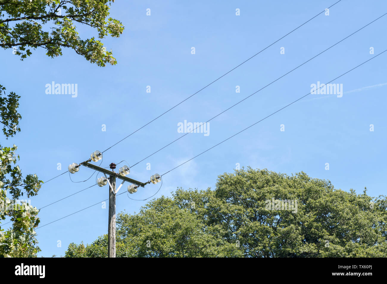 Rural electrical power lines in Cornwall, UK set against blue sky ...