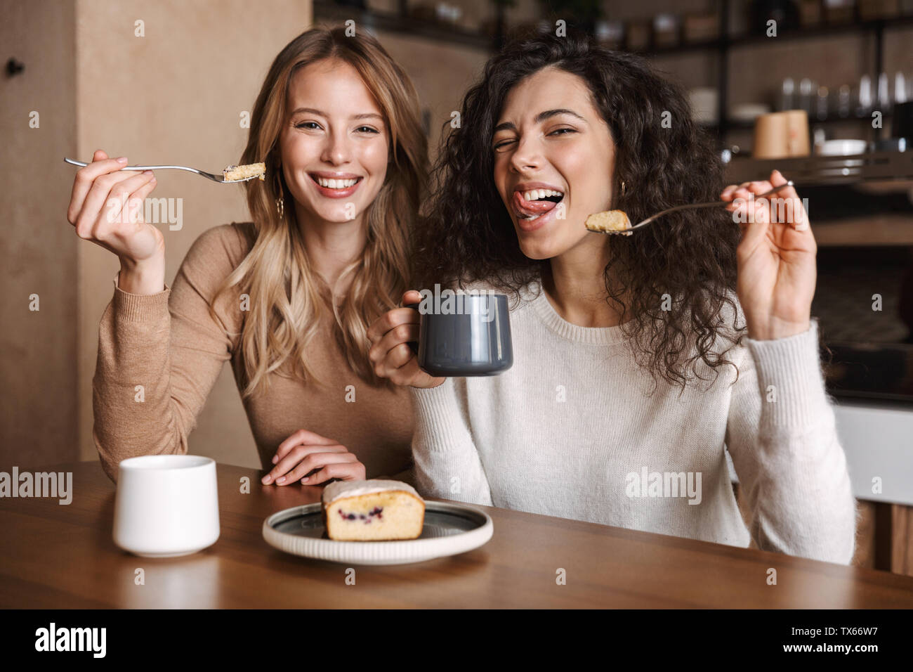 Image of excited happy pretty girls friends sitting in cafe drinking ...