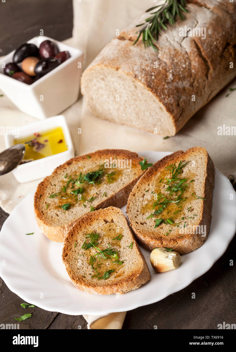 Sliced traditional toast bread with olive oil, olives, garlic and herbs ...