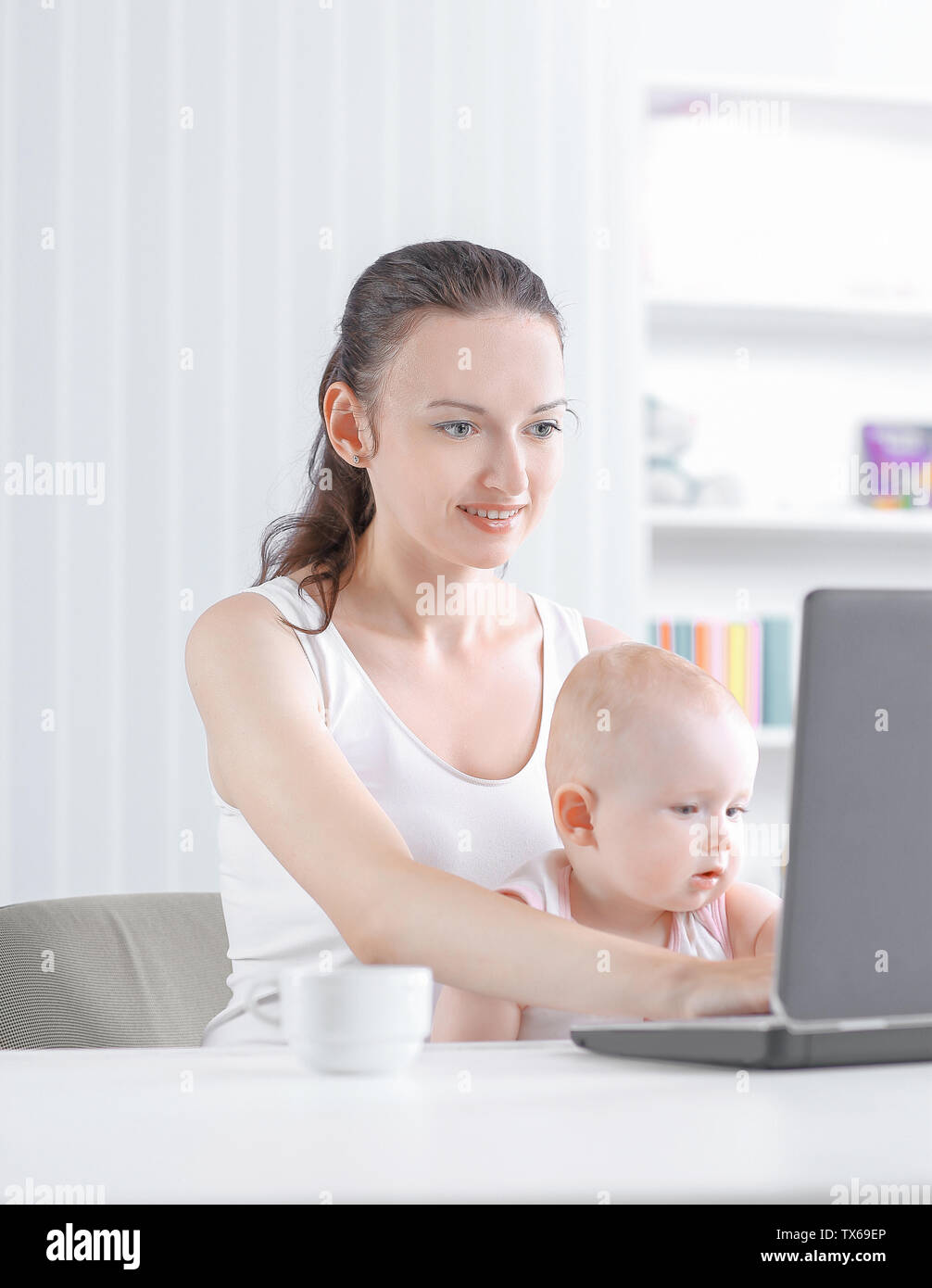 nice young working mother sitting at home and doing freelance work ...