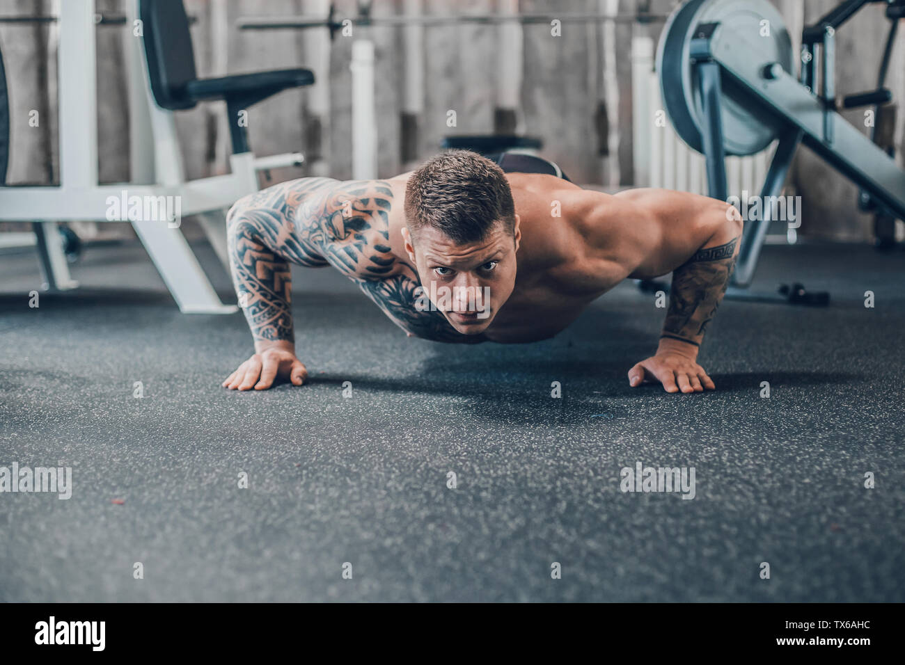 confident bodybuilder makes push-ups in the fitness room . photo with ...