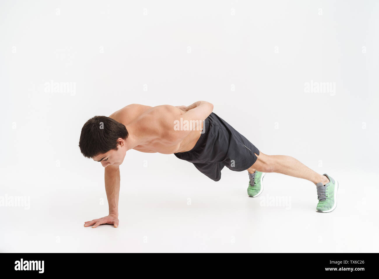 Full length of a healthy fit sportsman doing plank exercises isolated ...