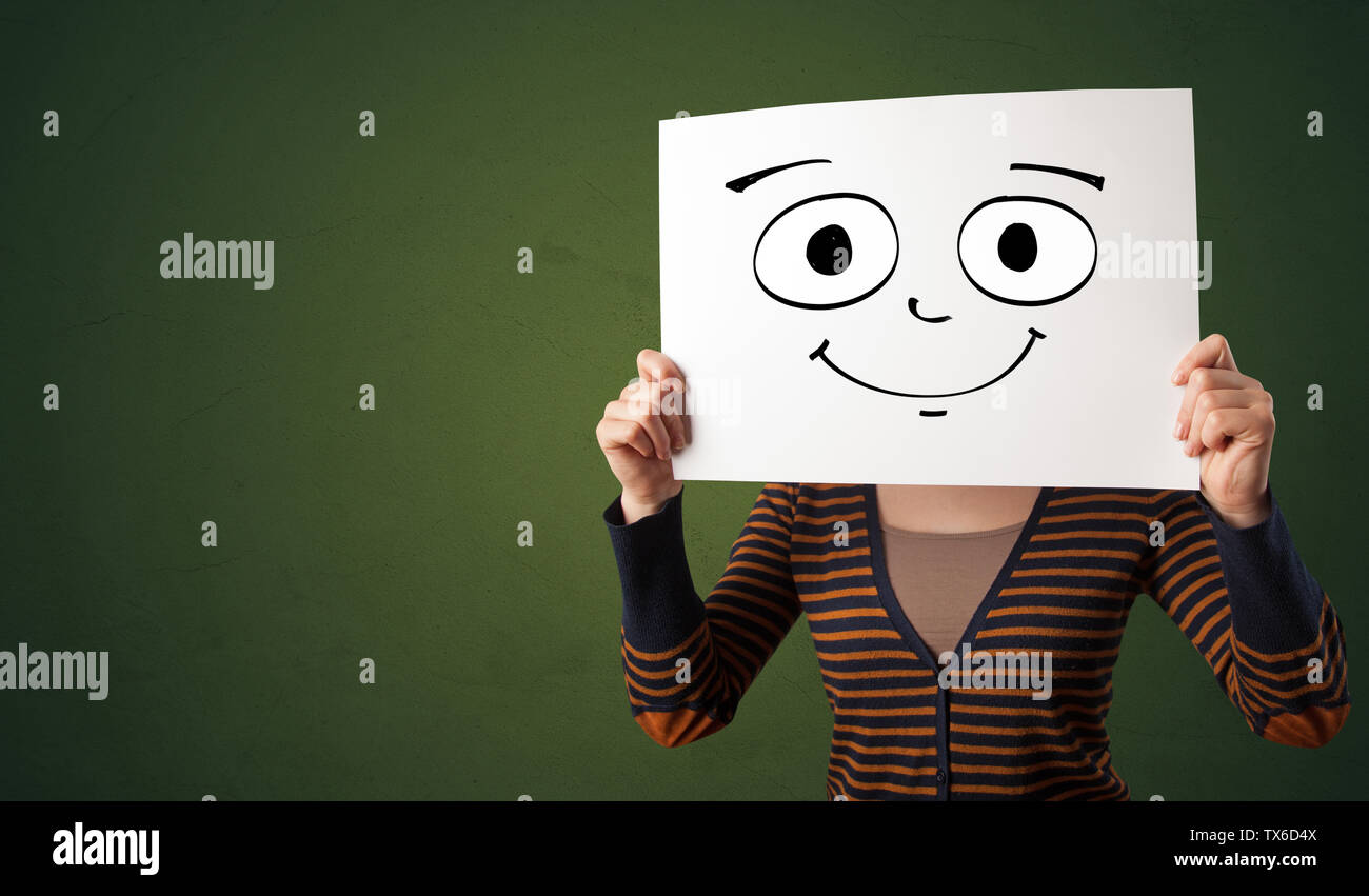 Young student holding a paper with laughing emoticon in front of his ...
