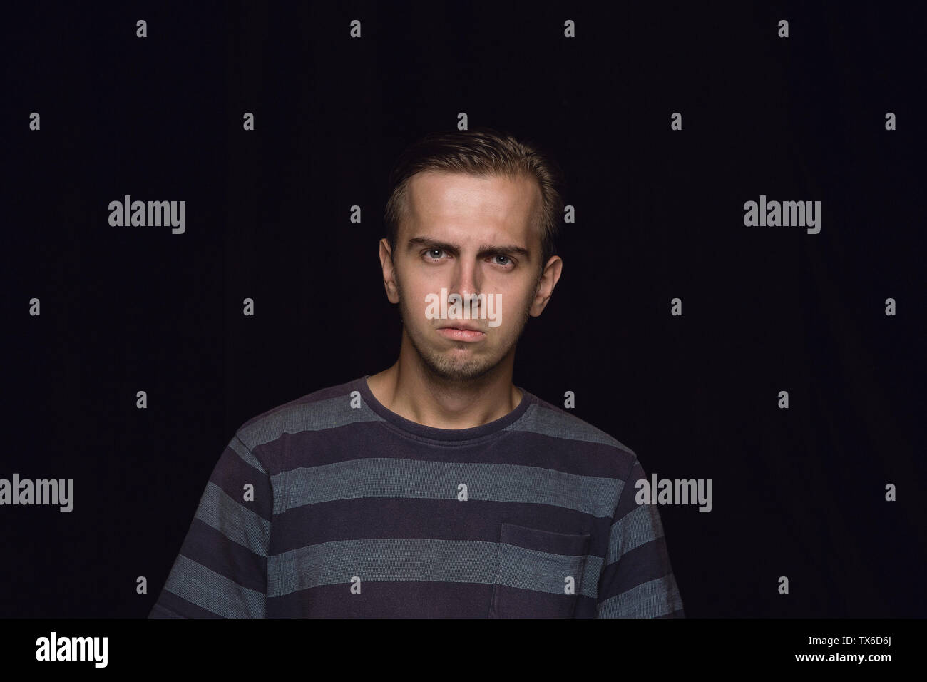 Close up portrait of young caucasian man isolated on black studio ...