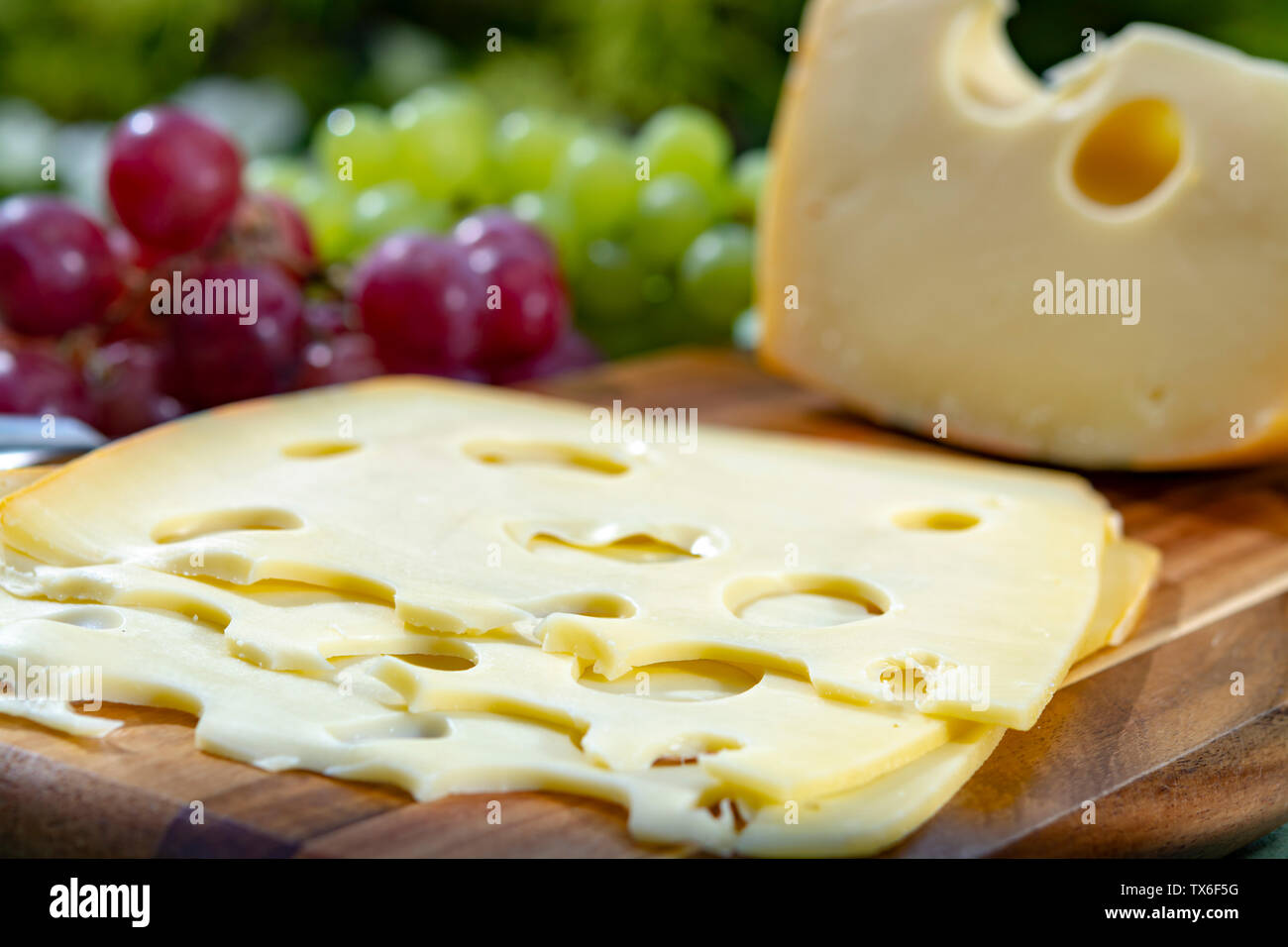 Dutch Maasdam hard cheese with holes, piece and sliced, served with ...