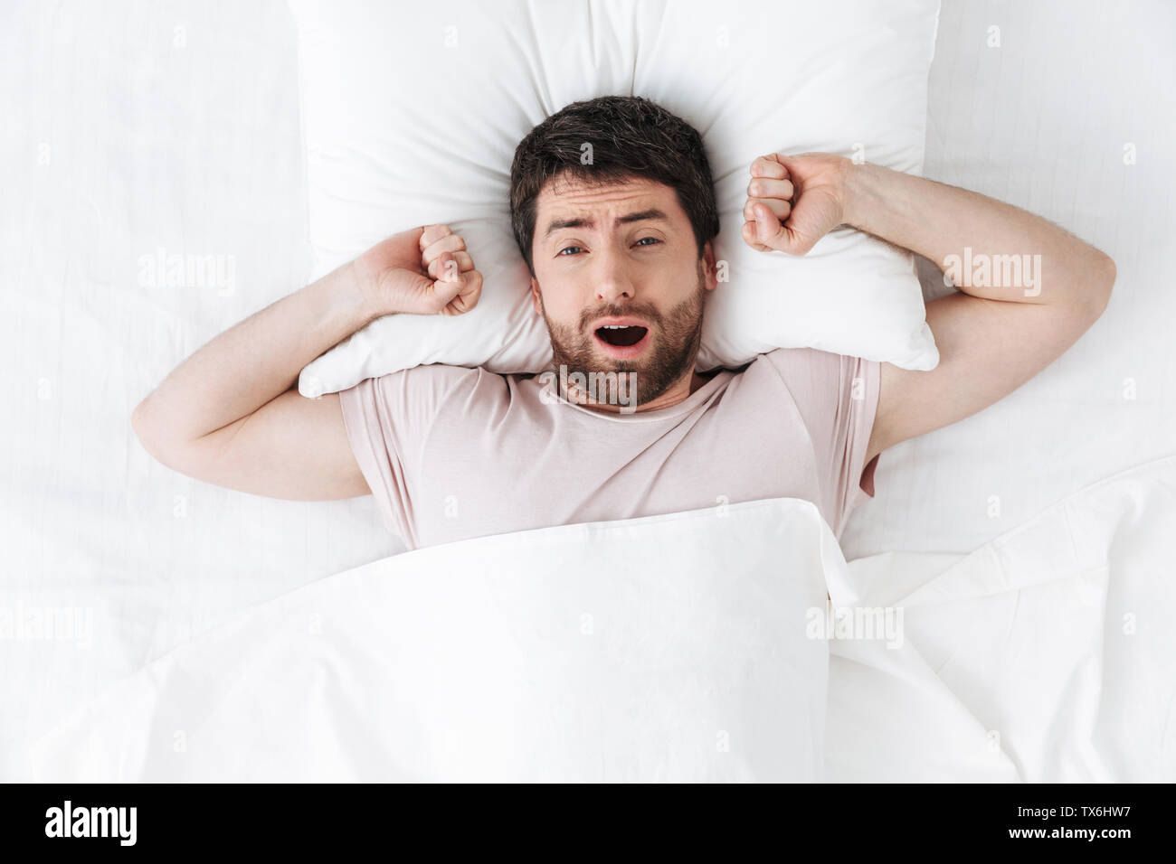 Young man yawning in bed hi-res stock photography and images - Alamy