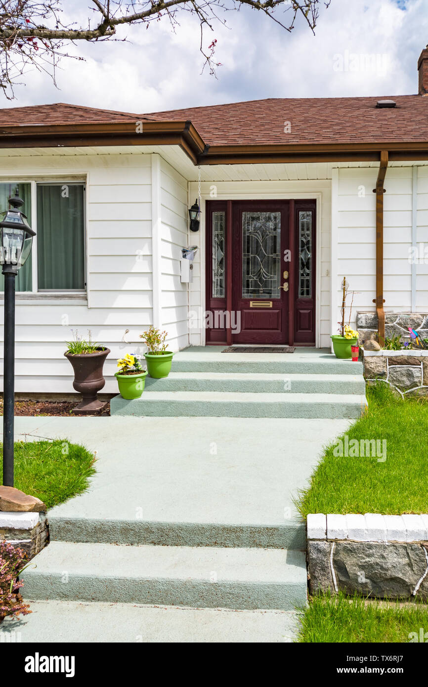Main entrance of nice family house with doorsteps and concrete pathway ...