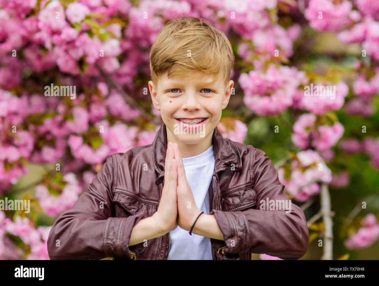 Namaste concept. Boy fashionable teen posing near sakura. Peaceful ...
