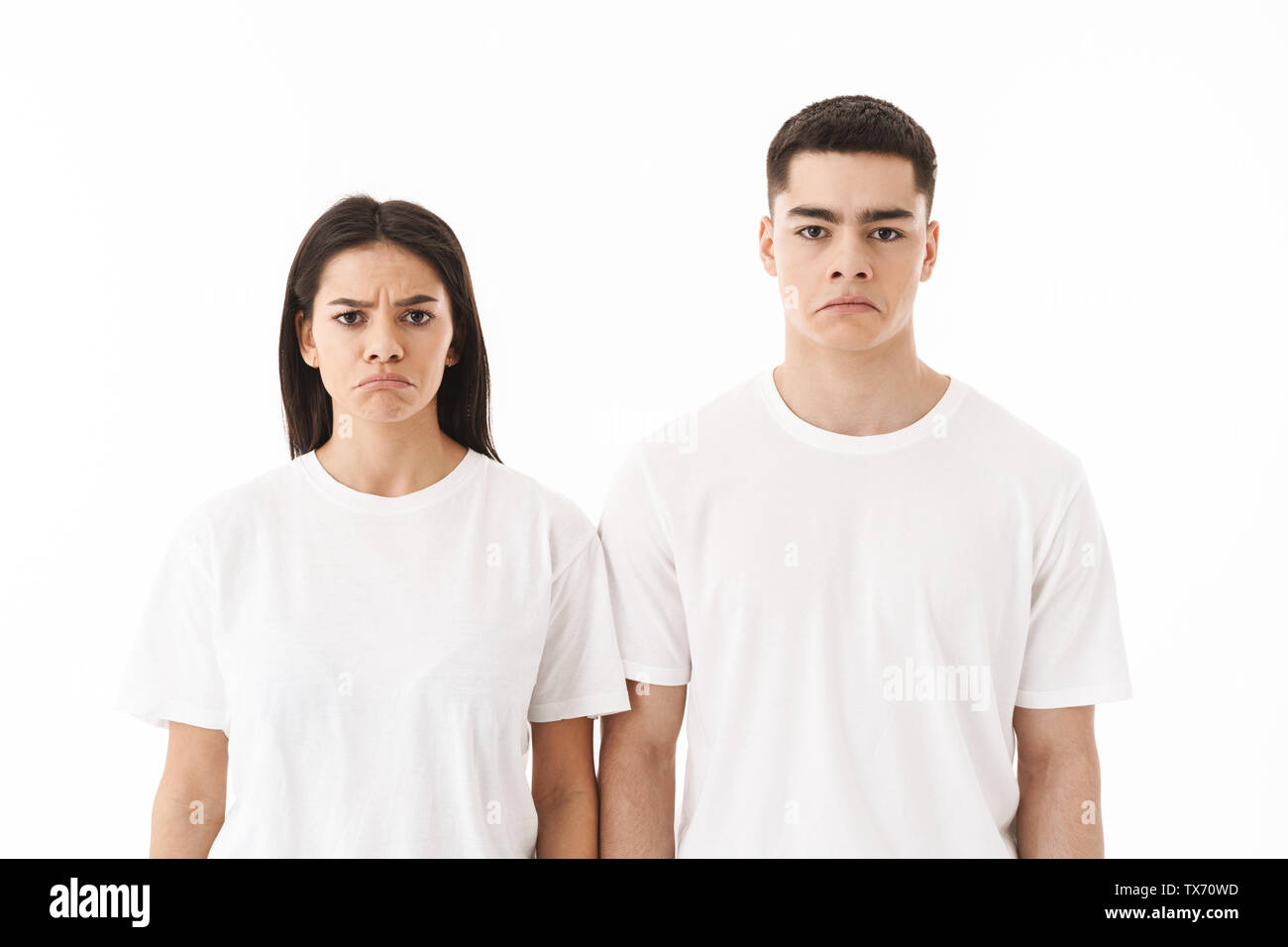 Portrait of a young upset casual wear couple standing isolated over ...