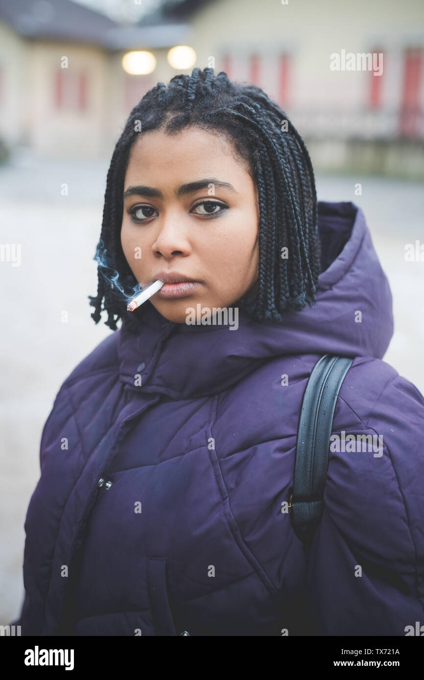 portrait of young african woman smoking cigarette - authenticity, youth ...