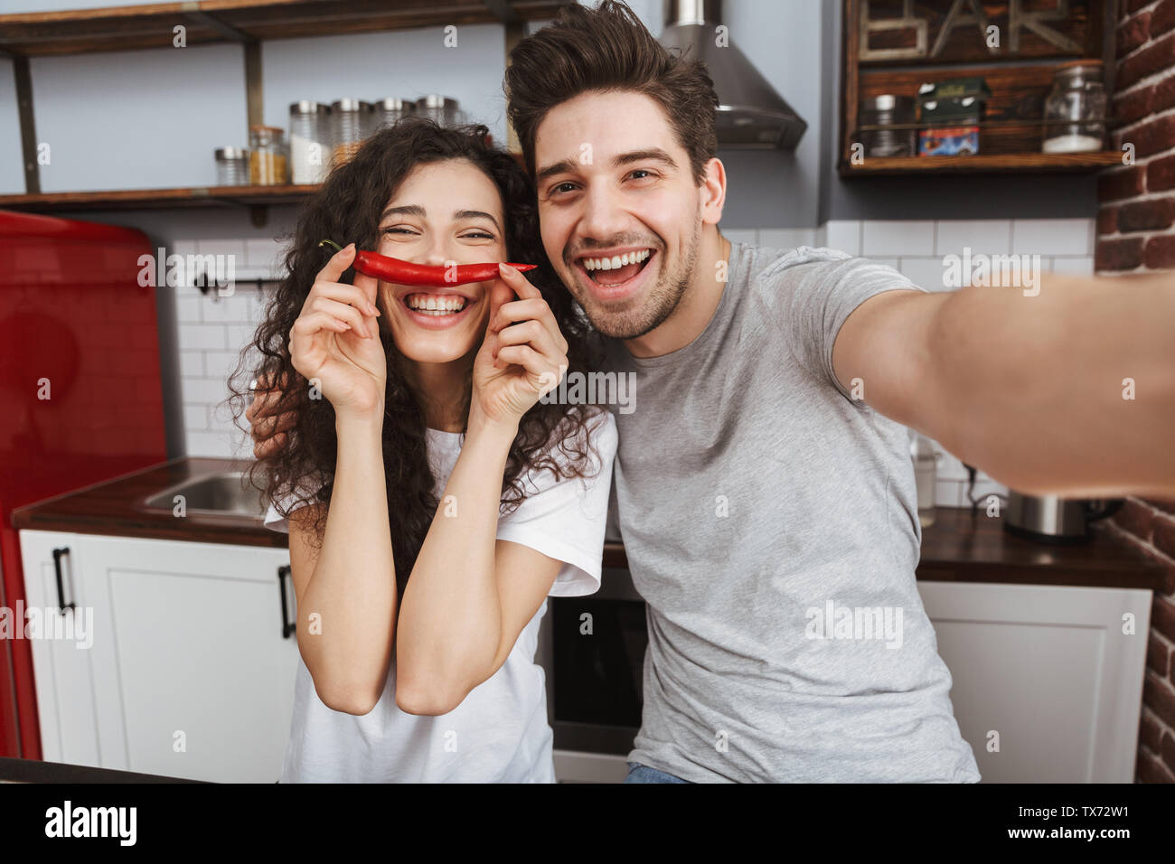 Cheerful couple at the kitchen, having fun, taking a selfie Stock Photo ...