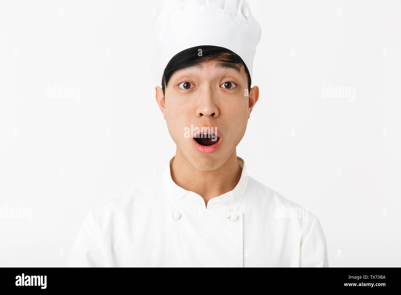 Confused asian chef wearing uniform standing isolated over white ...