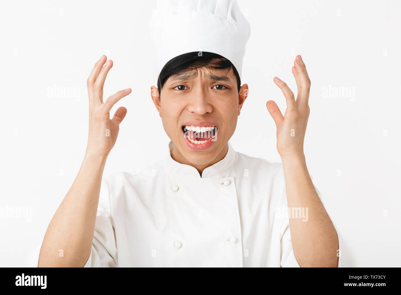 Confused asian chef wearing uniform standing isolated over white ...