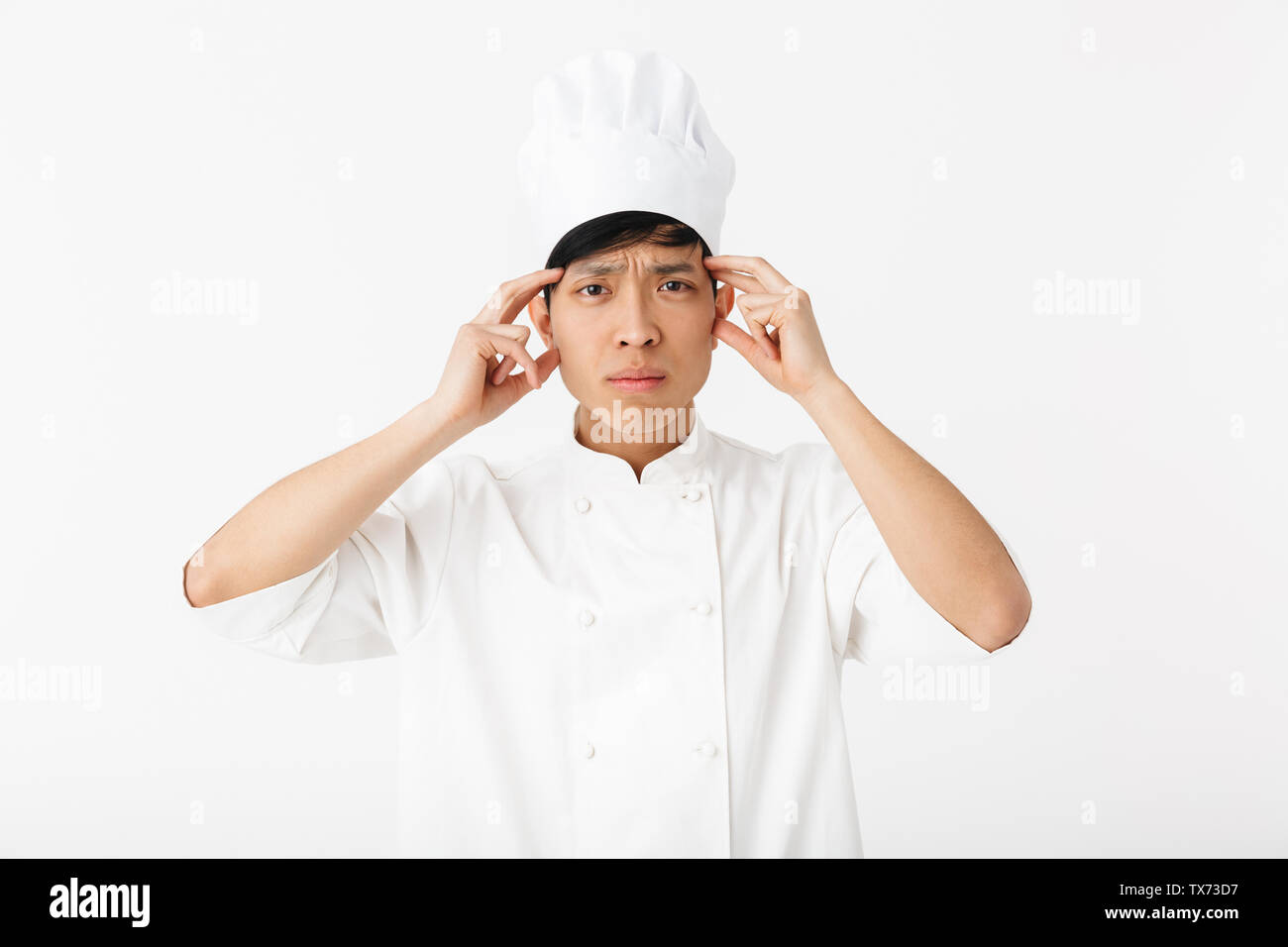 Confused asian chef wearing uniform standing isolated over white ...