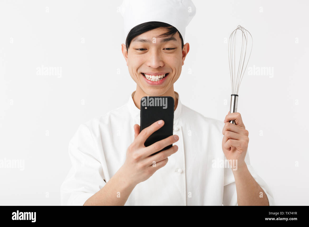 Excited asian chef wearing uniform standing isolated over white ...