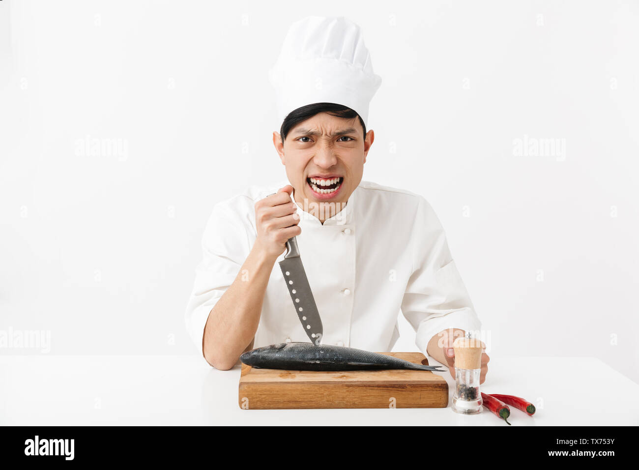 Image of tense japanese chief man in white cook uniform cooking and ...