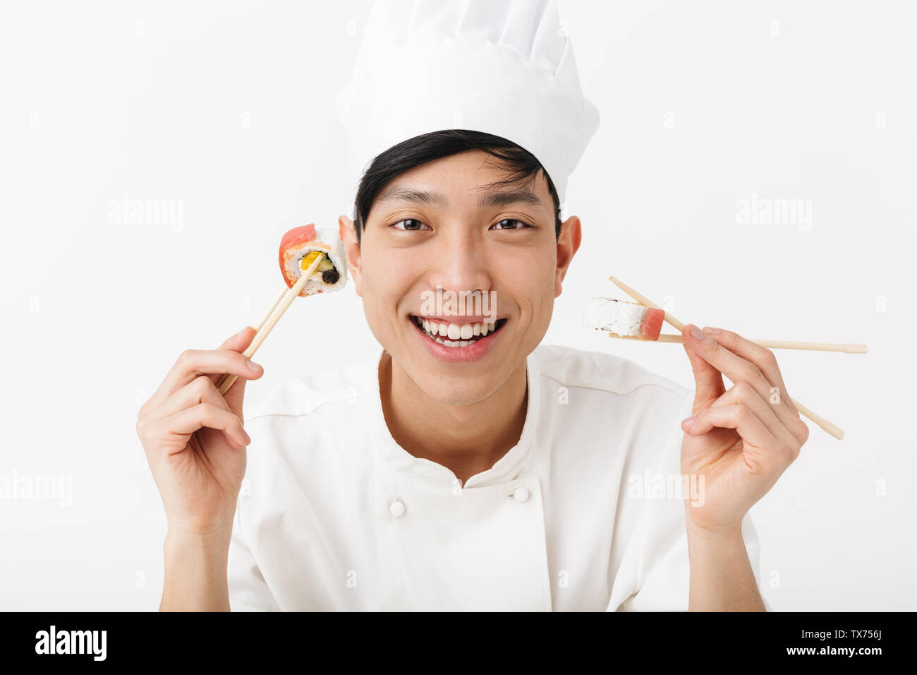 Image of funny asian chief man in white cook uniform eating sushi set ...