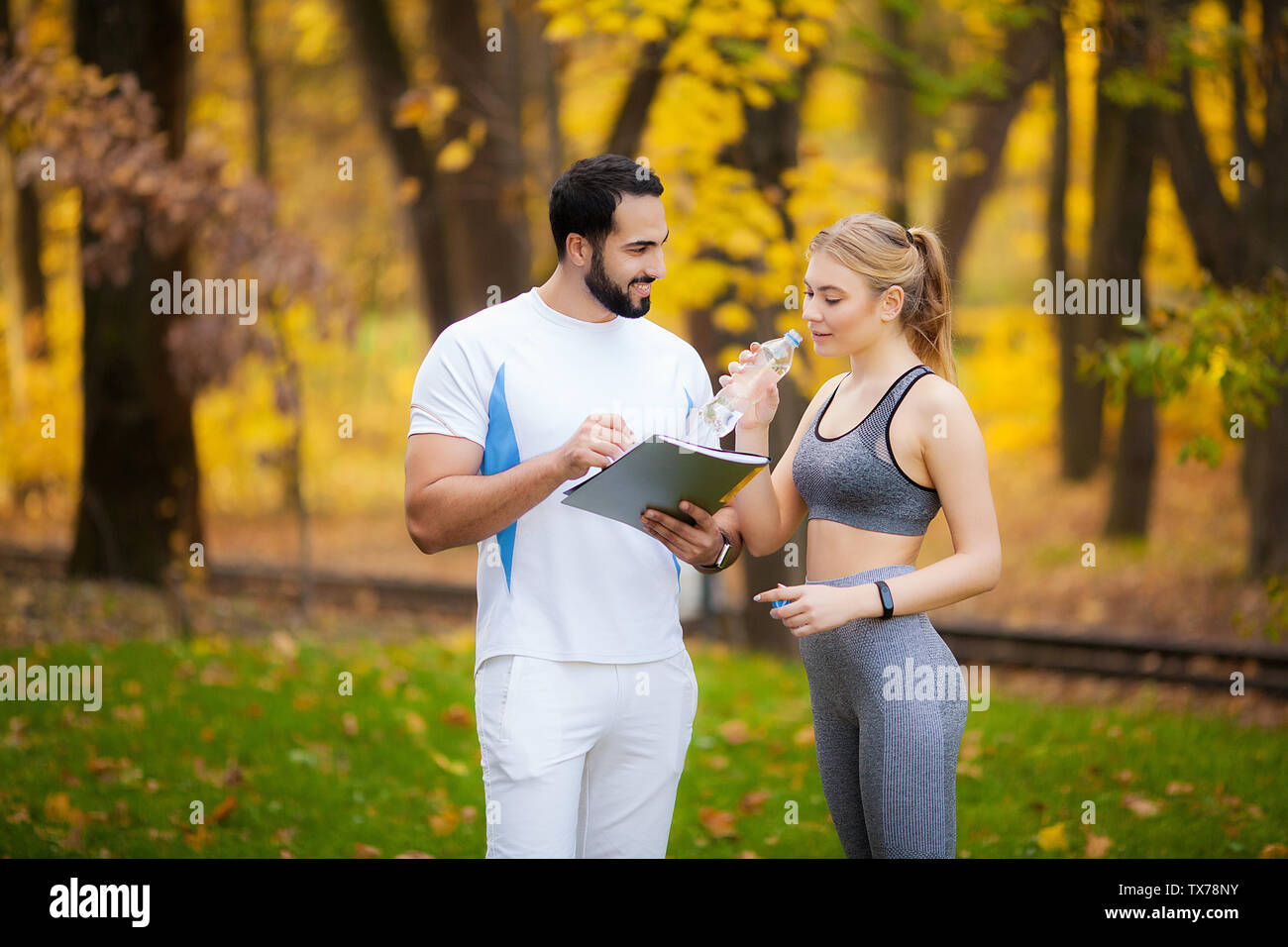 Fitness. Personal Trainer Takes Notes While Woman Exercising Outdoor ...
