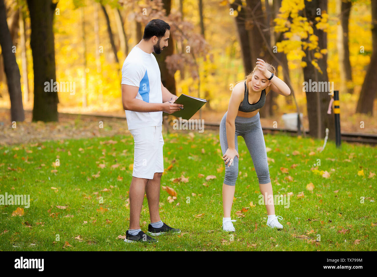 Fitness. Personal Trainer Takes Notes While Woman Exercising Outdoor ...