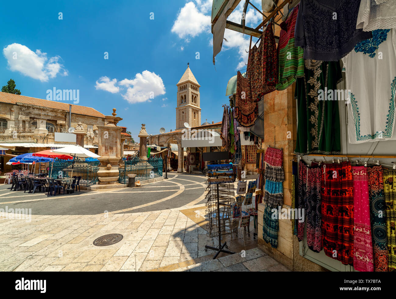 Small square with fountain among gift shops as belfry on background in ...