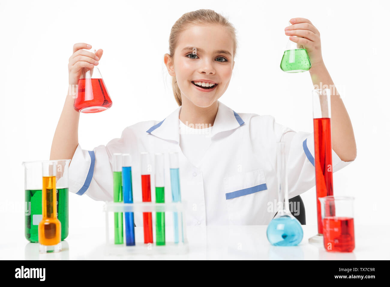 Portrait of pretty little girl in white laboratory coat making chemical ...